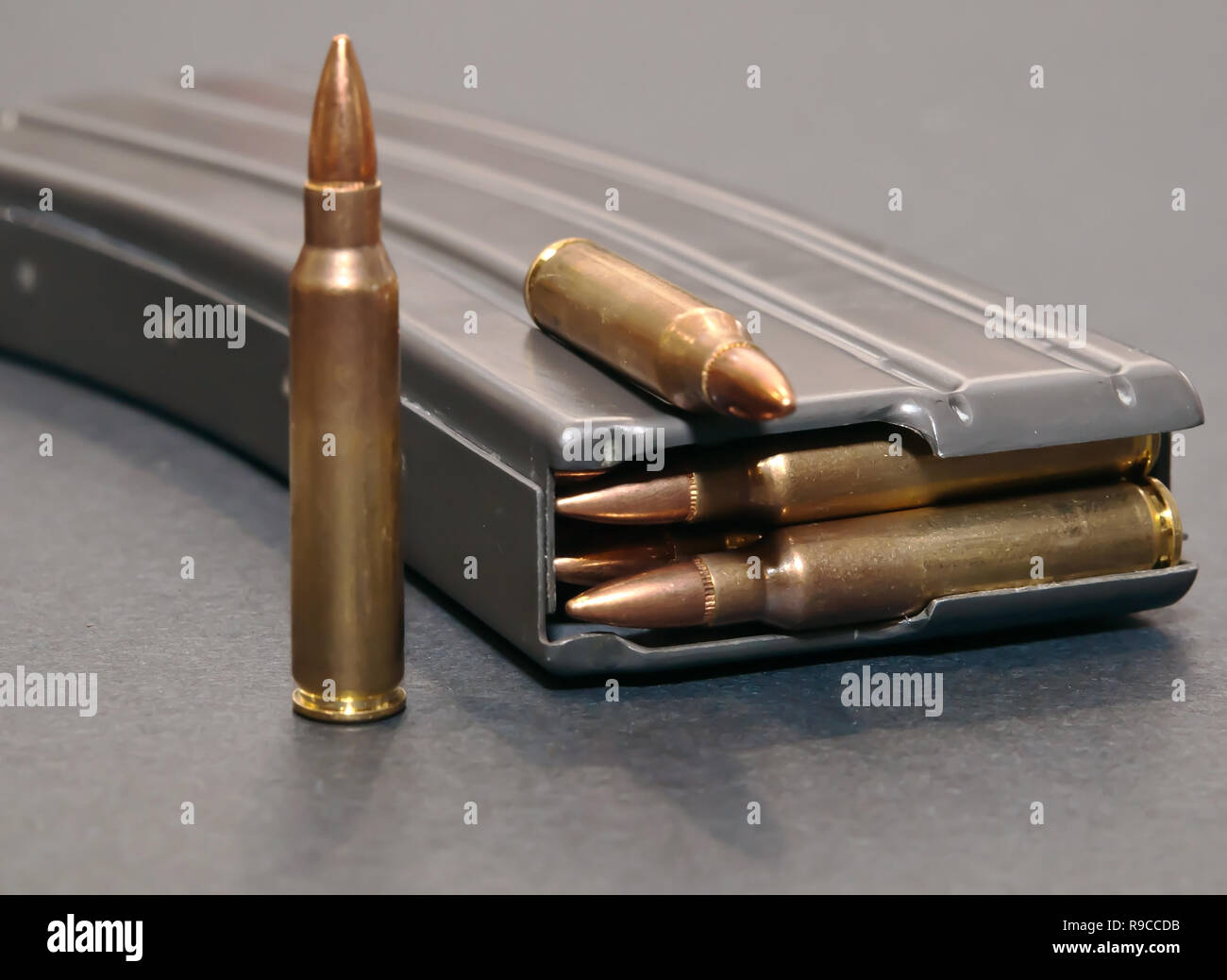 A rifle magazine loaded with .223 bullets on a gray background with two ...