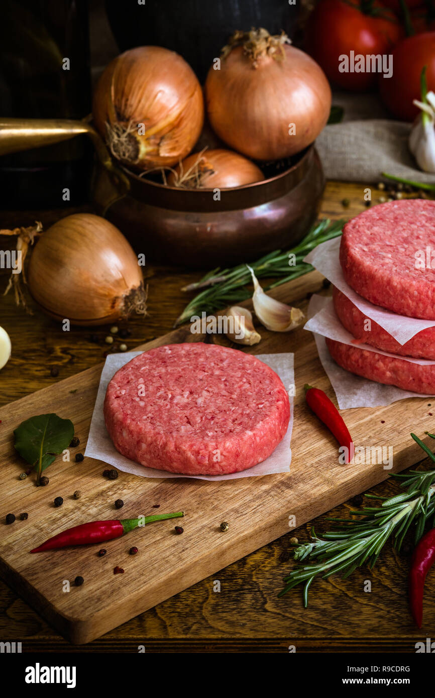 Raw beef burger, traditional barbecue, still life with vegetables and ...