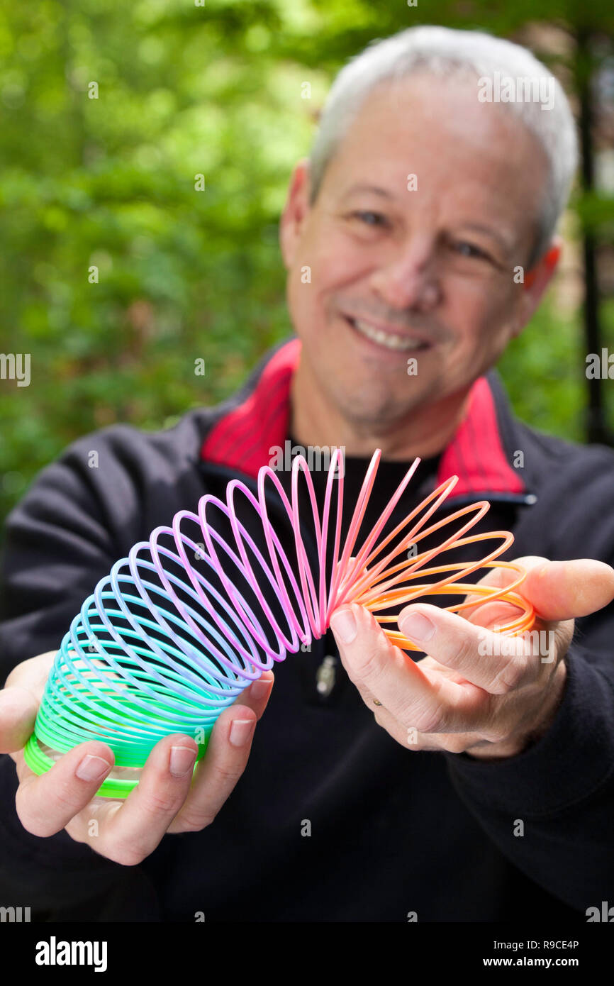 Mature man showing a toy slinky, USA Stock Photo - Alamy