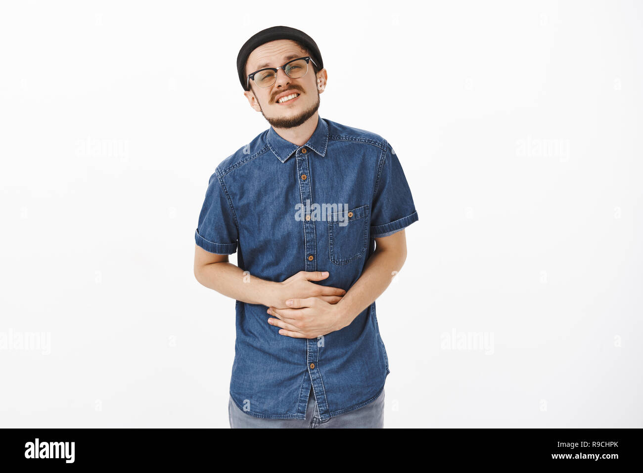 Troubled young guy eating rotten food holding hands on belly suffering ...