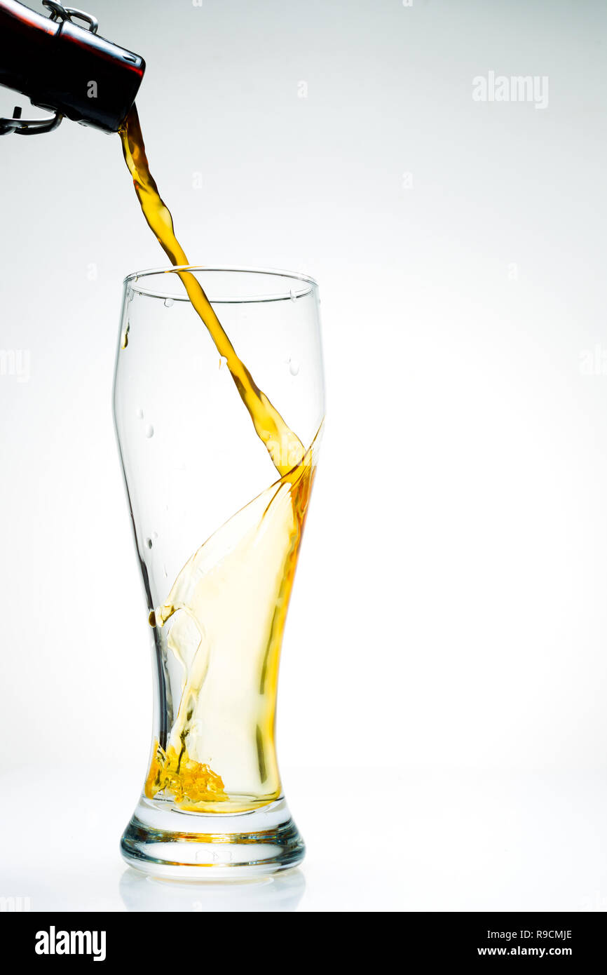 Beer is pouring from a bottle into an empty glass, white background ...