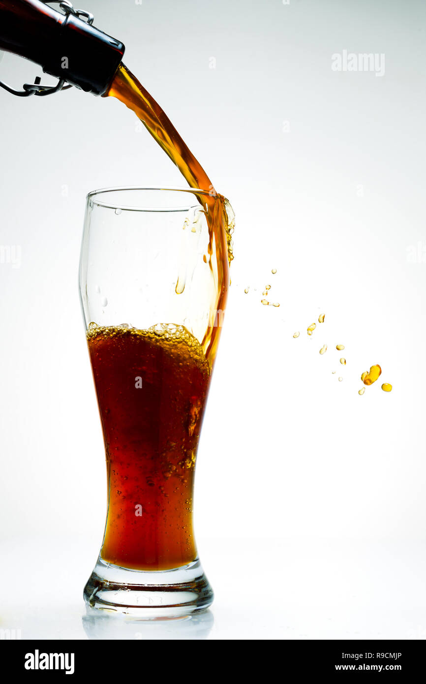 Beer is pouring from a bottle into an empty glass, white background ...