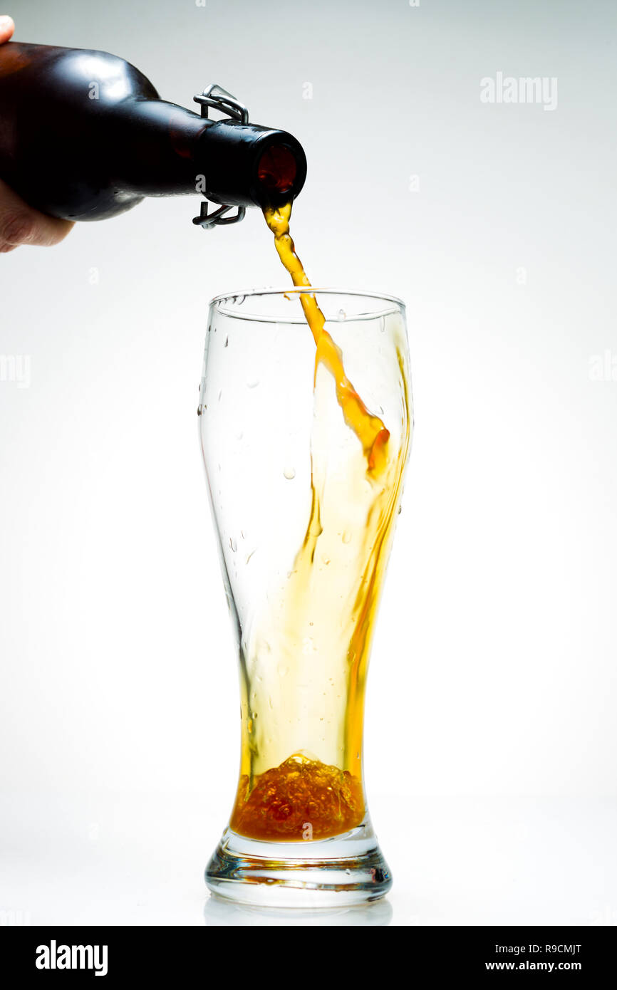 Beer is pouring from a bottle into an empty glass, white background ...