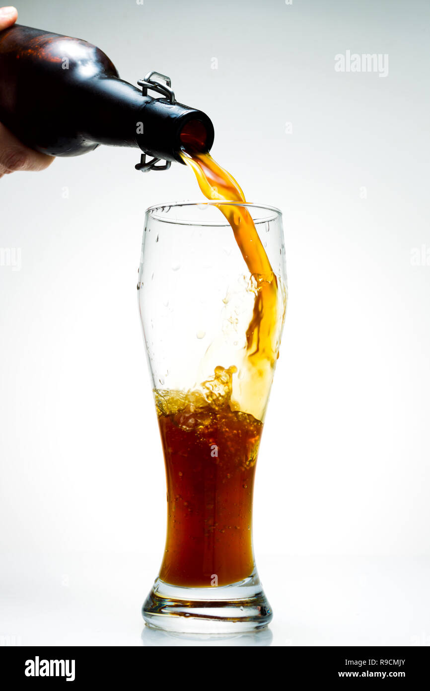 Beer is pouring from a bottle into an empty glass, white background ...