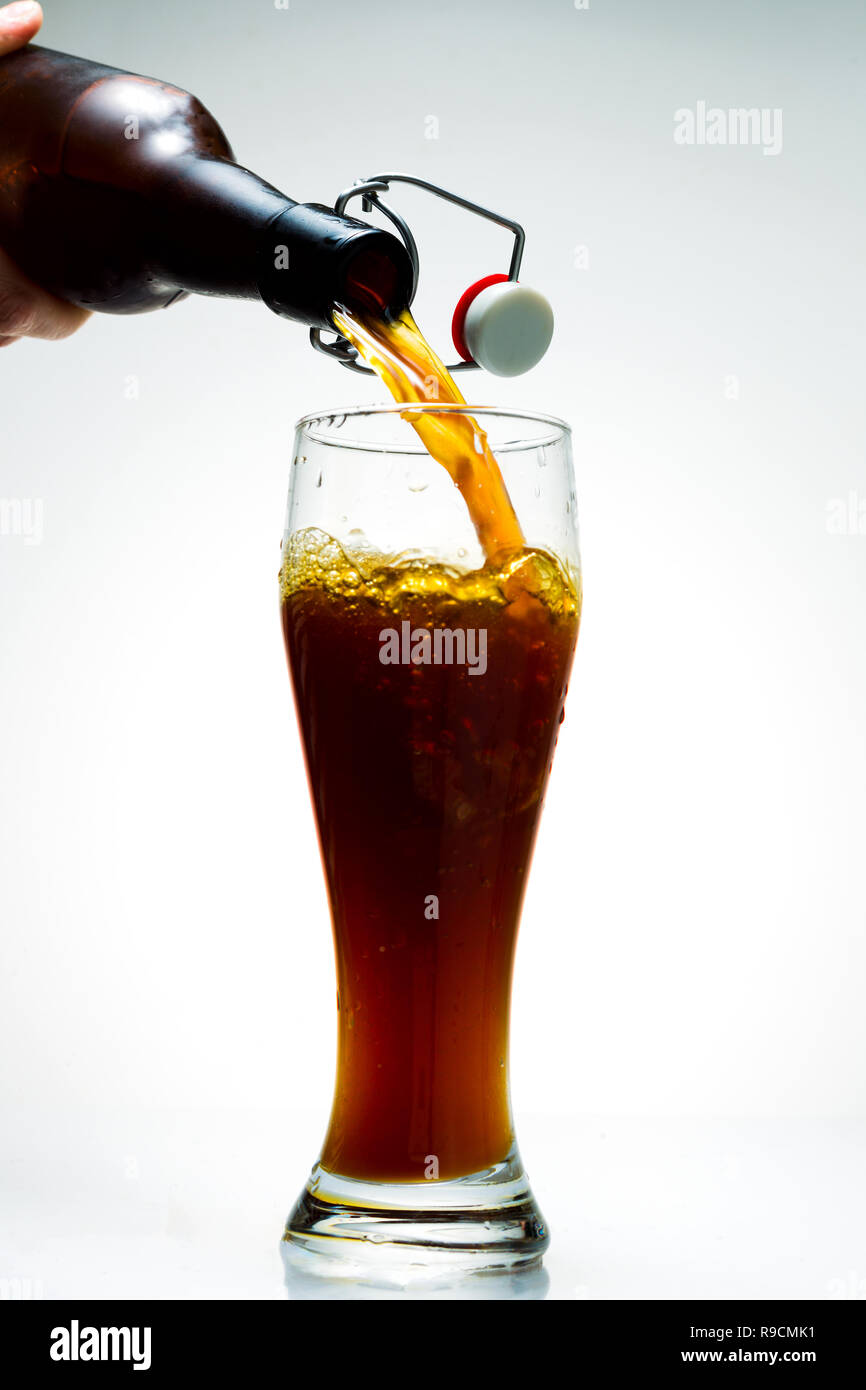 Beer is pouring from a bottle into an empty glass, white background ...
