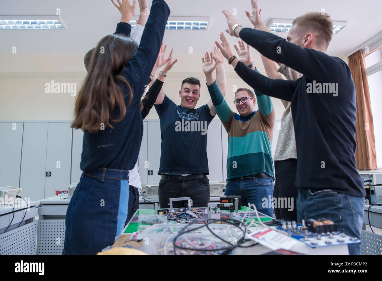 Group of young students in electronics classroom celebrating ...
