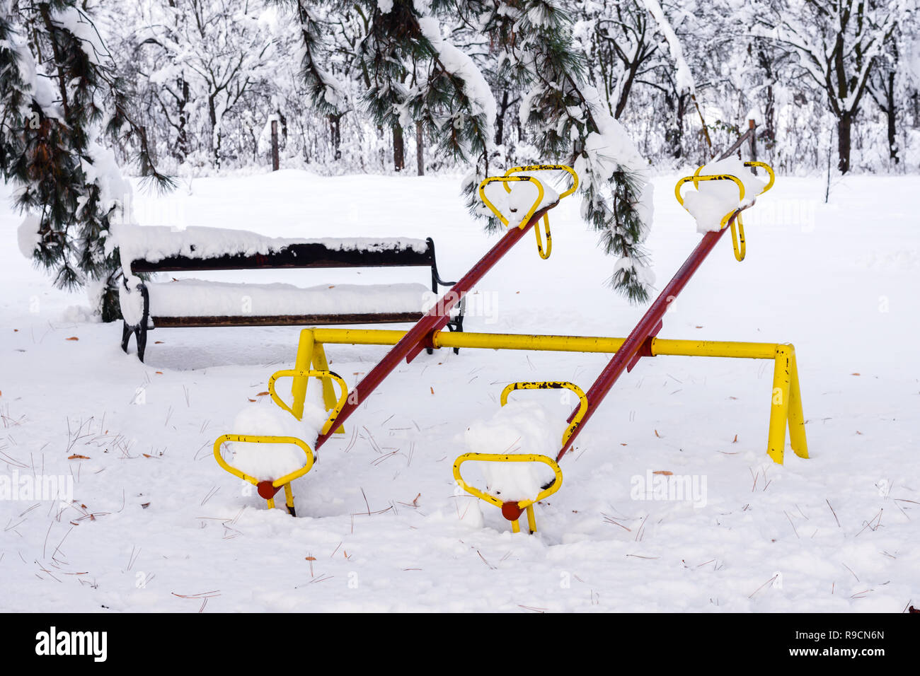 A red yellow teeter covered with snow under the pine in the park Stock ...