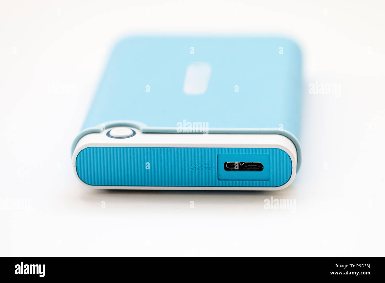 Portable external hard drive on plain white background. Light blue in ...