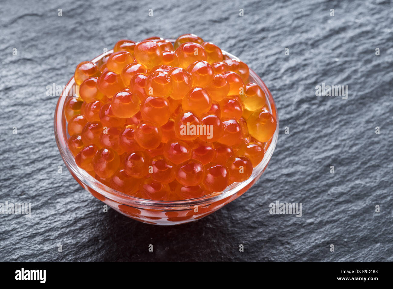 Red caviar in the bowl on gray graphite background. Macro picture. Top ...