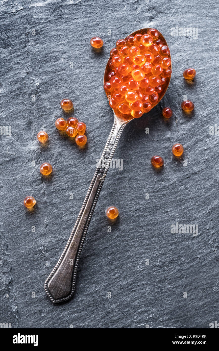 Silver spoon of red caviar on gray graphite background. Macro picture ...
