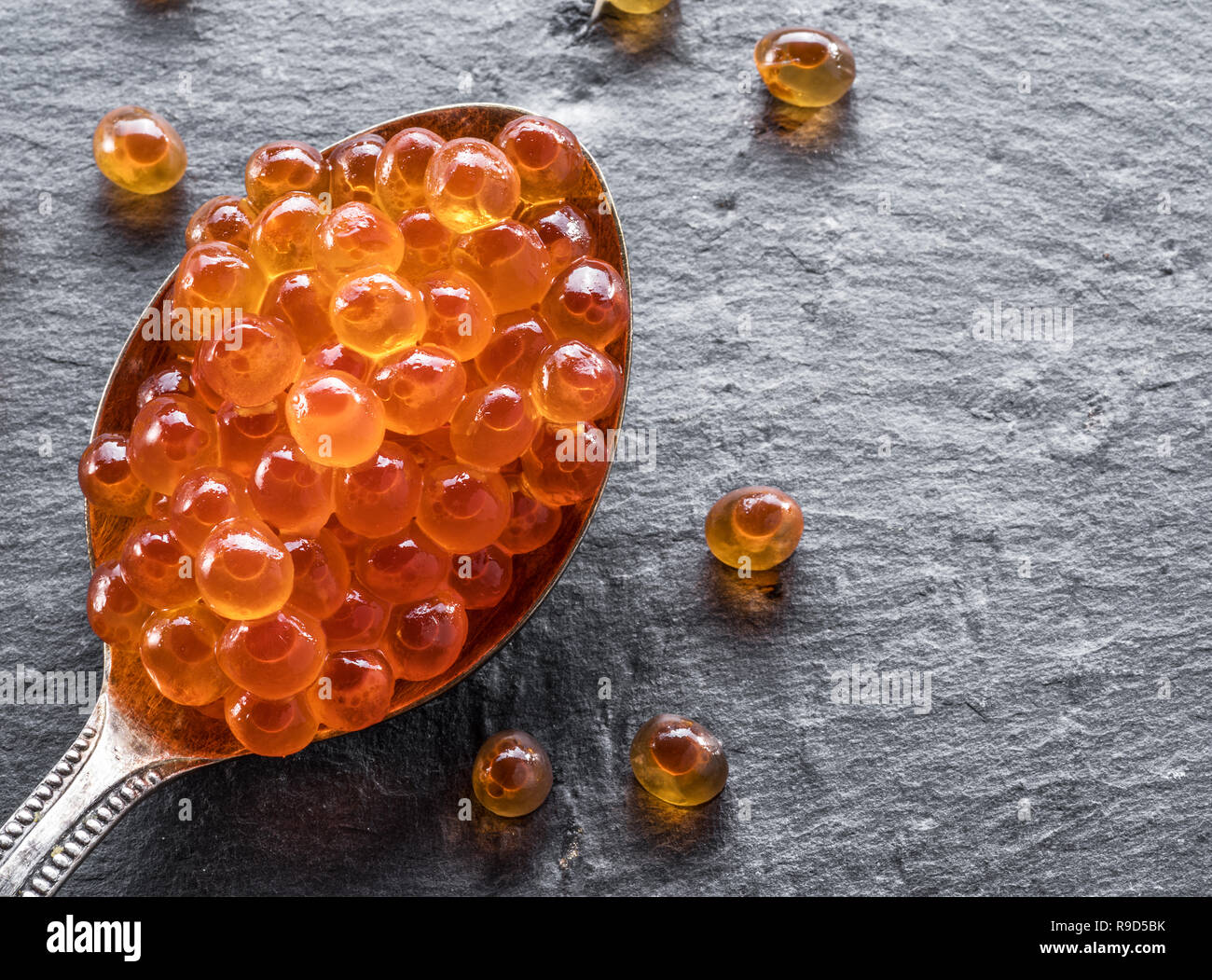 Silver spoon of red caviar on gray graphite background. Macro picture ...