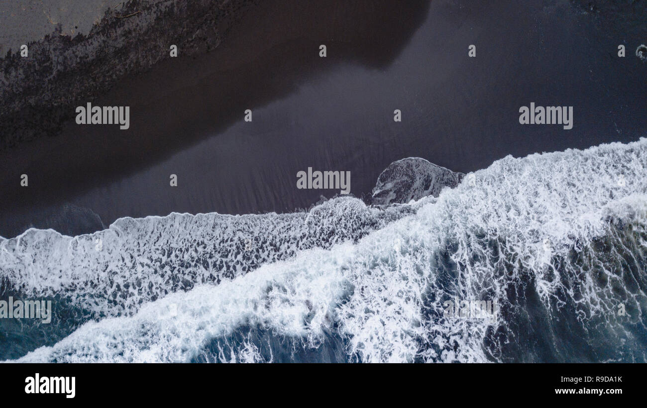Overhead shots of waves crashing onto a black sand beach on the big ...