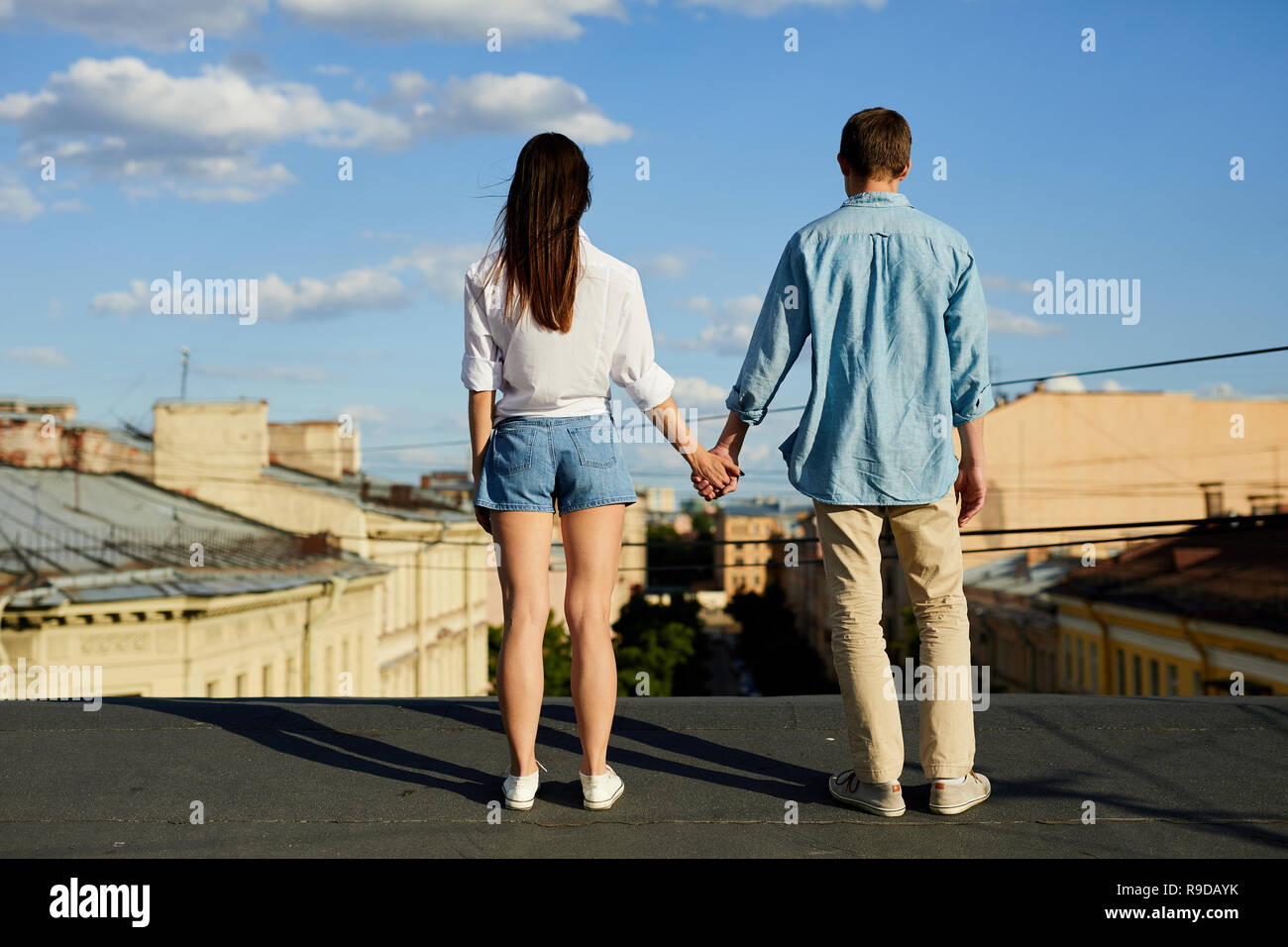 Couple holding hands on roof Stock Photo - Alamy