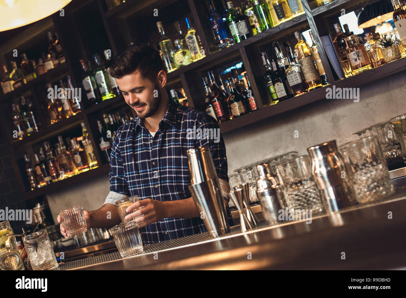 Young barman standing at bar counter serving cocktails smiling happy ...