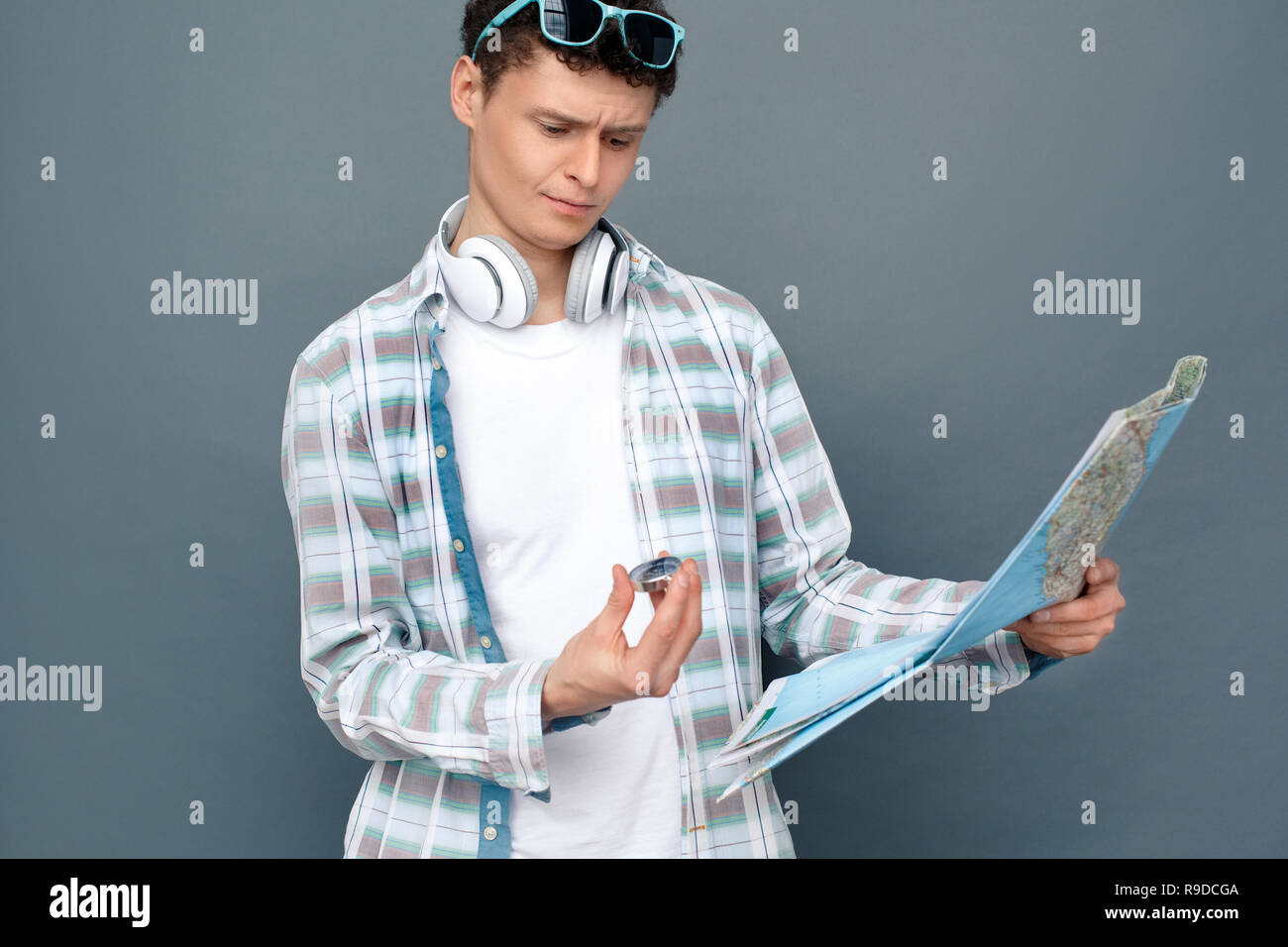 Young guy isolated on gray wall tourism concept standing holding map ...