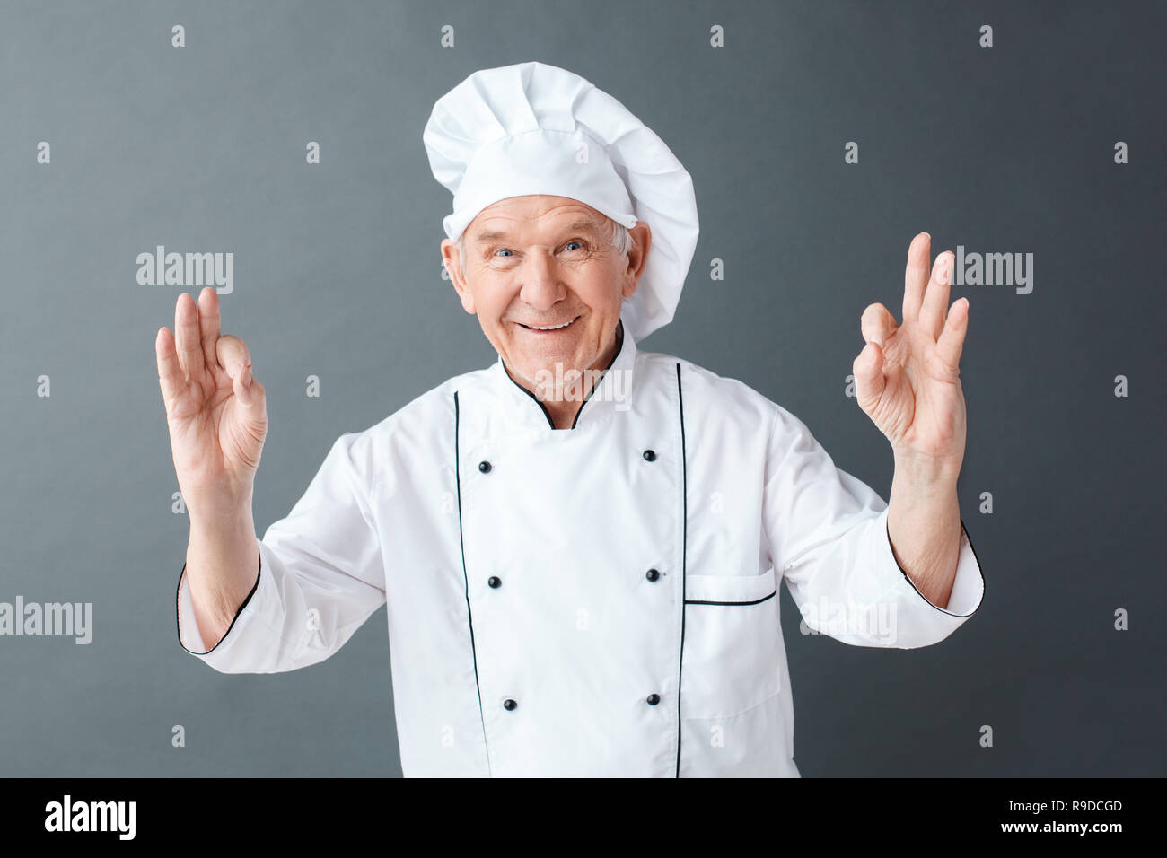 Senior male chef studio standing isolated on gray wall showing ok ...