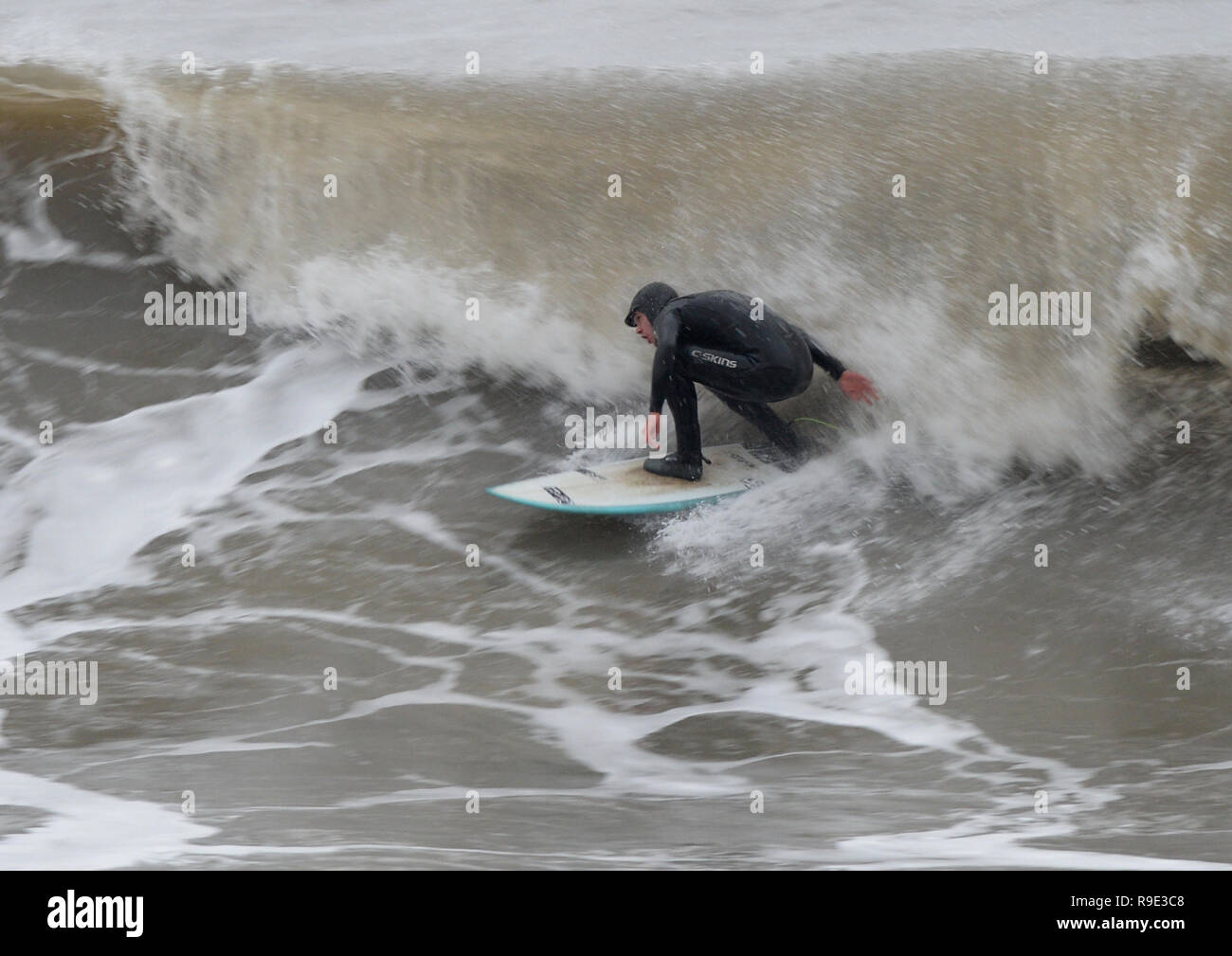 Surfer racing across the face of a breaking wave in full wetsuit Stock ...