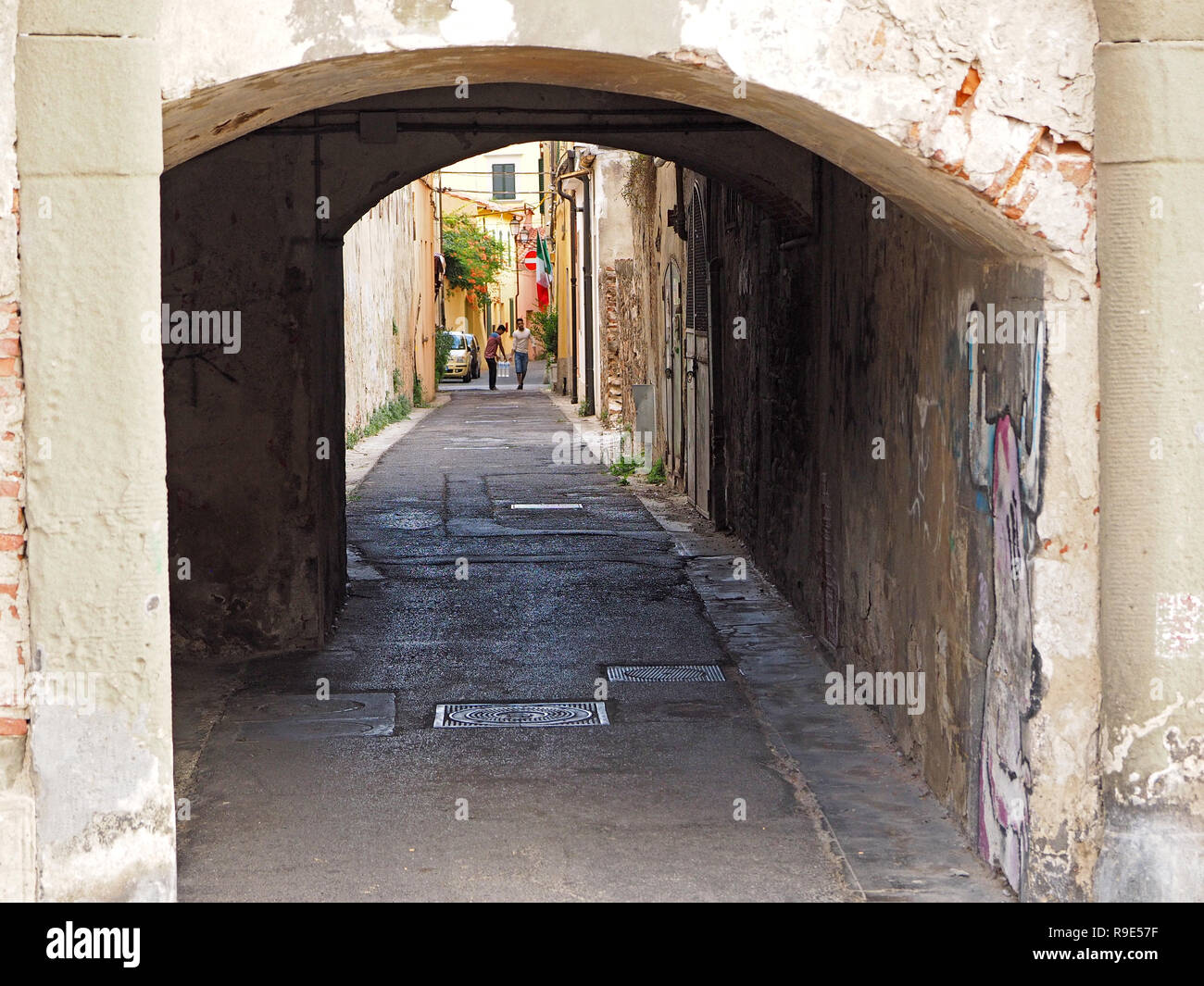 two men carry pack of bottled water below shuttered windows in typical ...