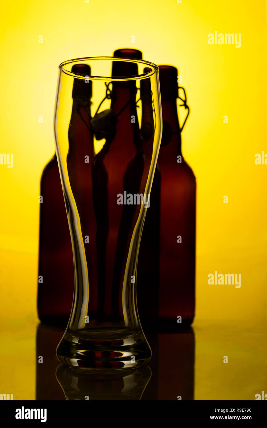 Empty beer glass and empty beer bottles on a color background, studio ...