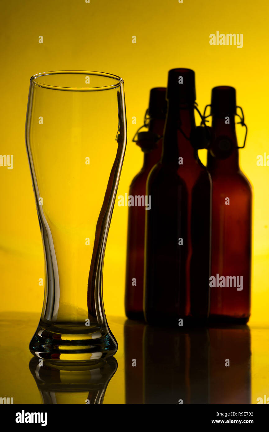 Empty beer glass and empty beer bottles on a color background, studio ...
