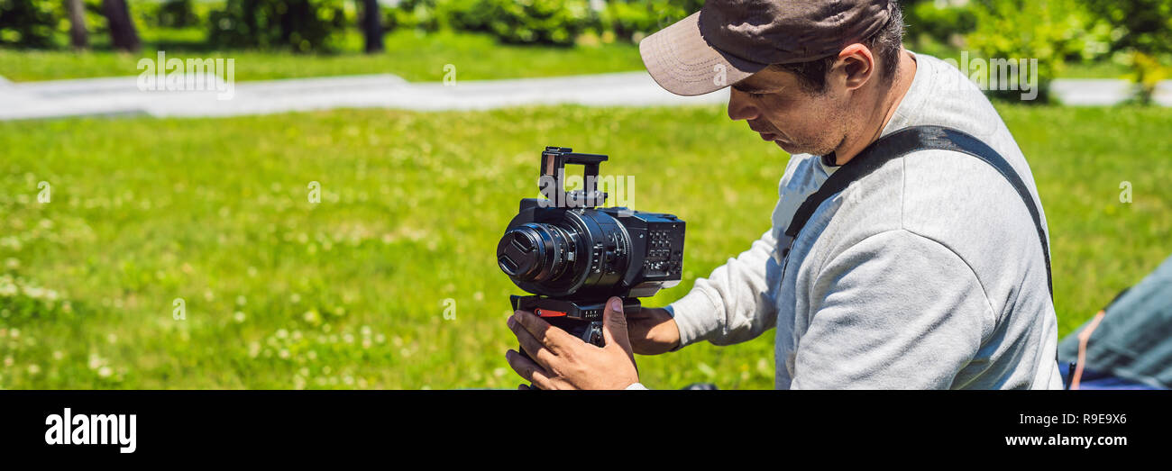 a professional cameraman prepares a camera and a tripod before shooting ...