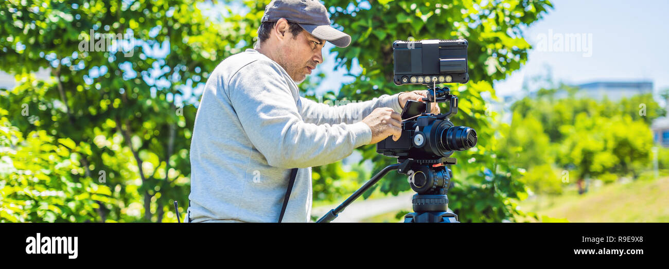 a professional cameraman prepares a camera and a tripod before shooting ...