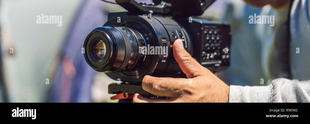 a professional cameraman prepares a camera and a tripod before shooting ...