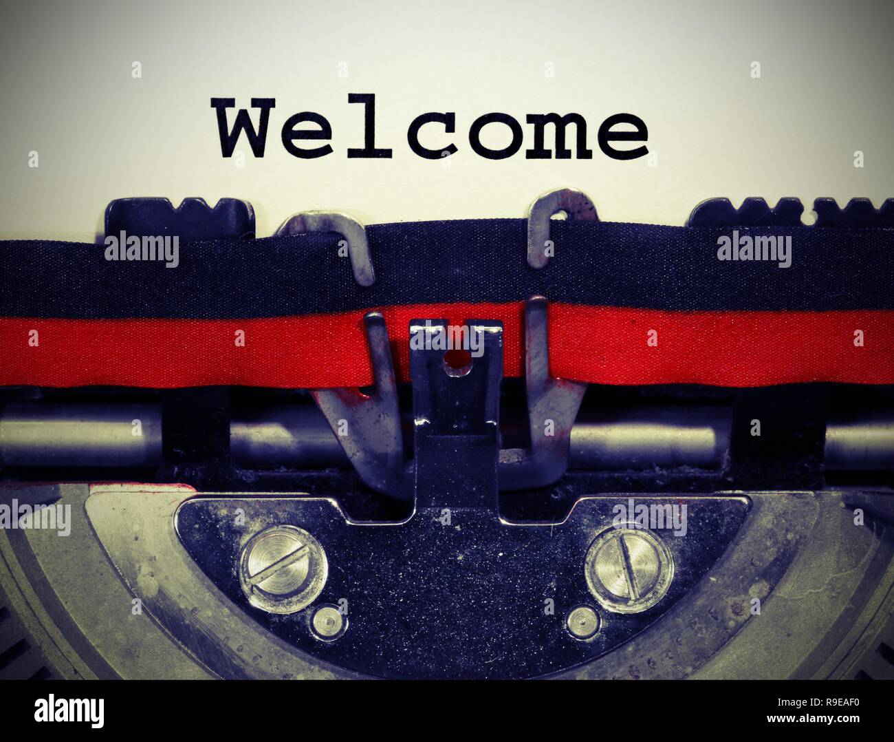 Welcom text with the typewriter on white sheet with old toned effect ...