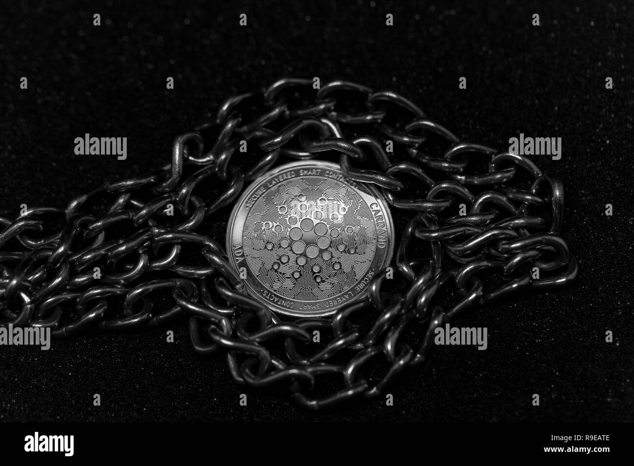 Cardano cryptocurrency physical coin surrounded with metal chain on the ...