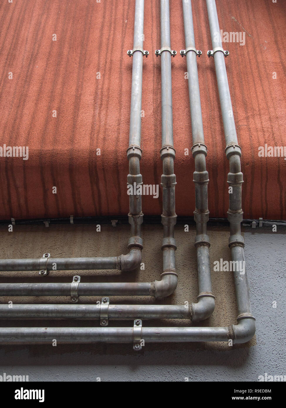 water pipeline made of metal pipes and fittings follow the wall of a ...