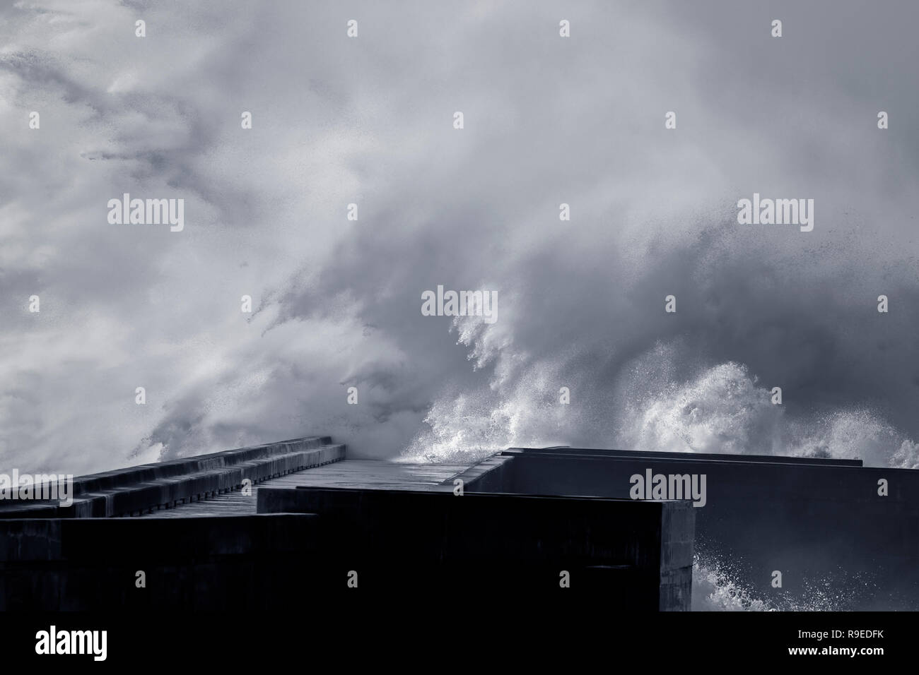 Closeup of a huge stormy wave spash over a pier from the north of ...