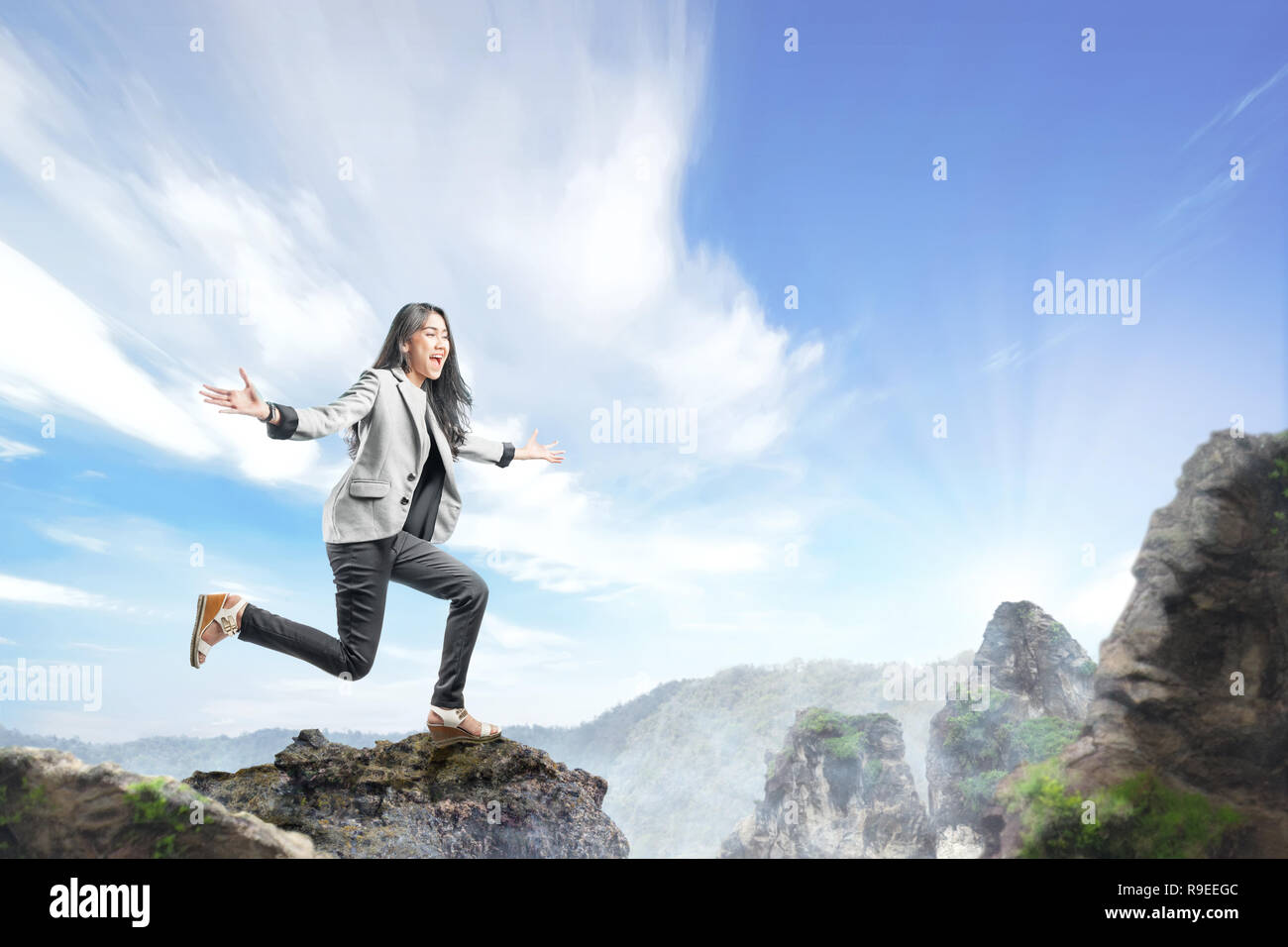 Young asian business woman in formal suit jumping on the top of ...