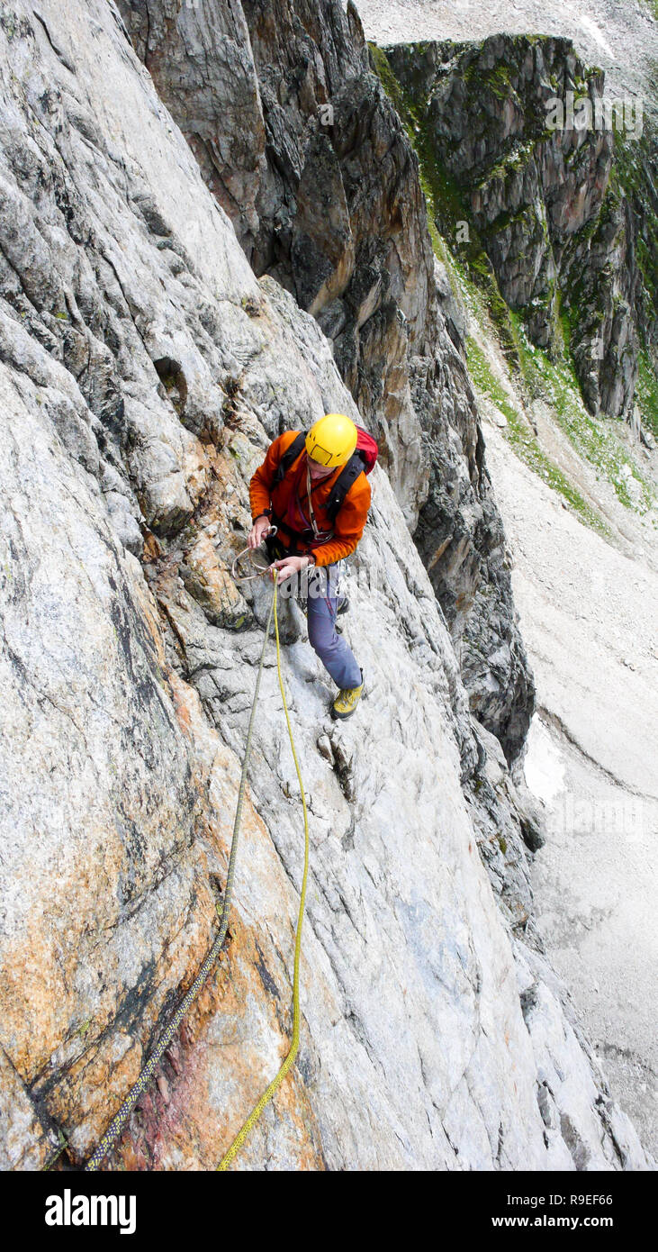 rock climber on a hard alpine route in the Alps of Switzerland placing ...
