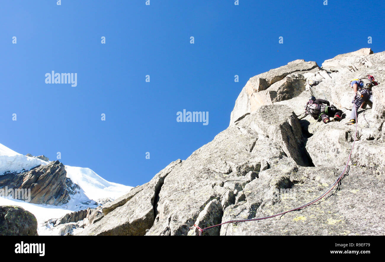 mountain guide looking up on a rocky climb in the French Alps with rope ...