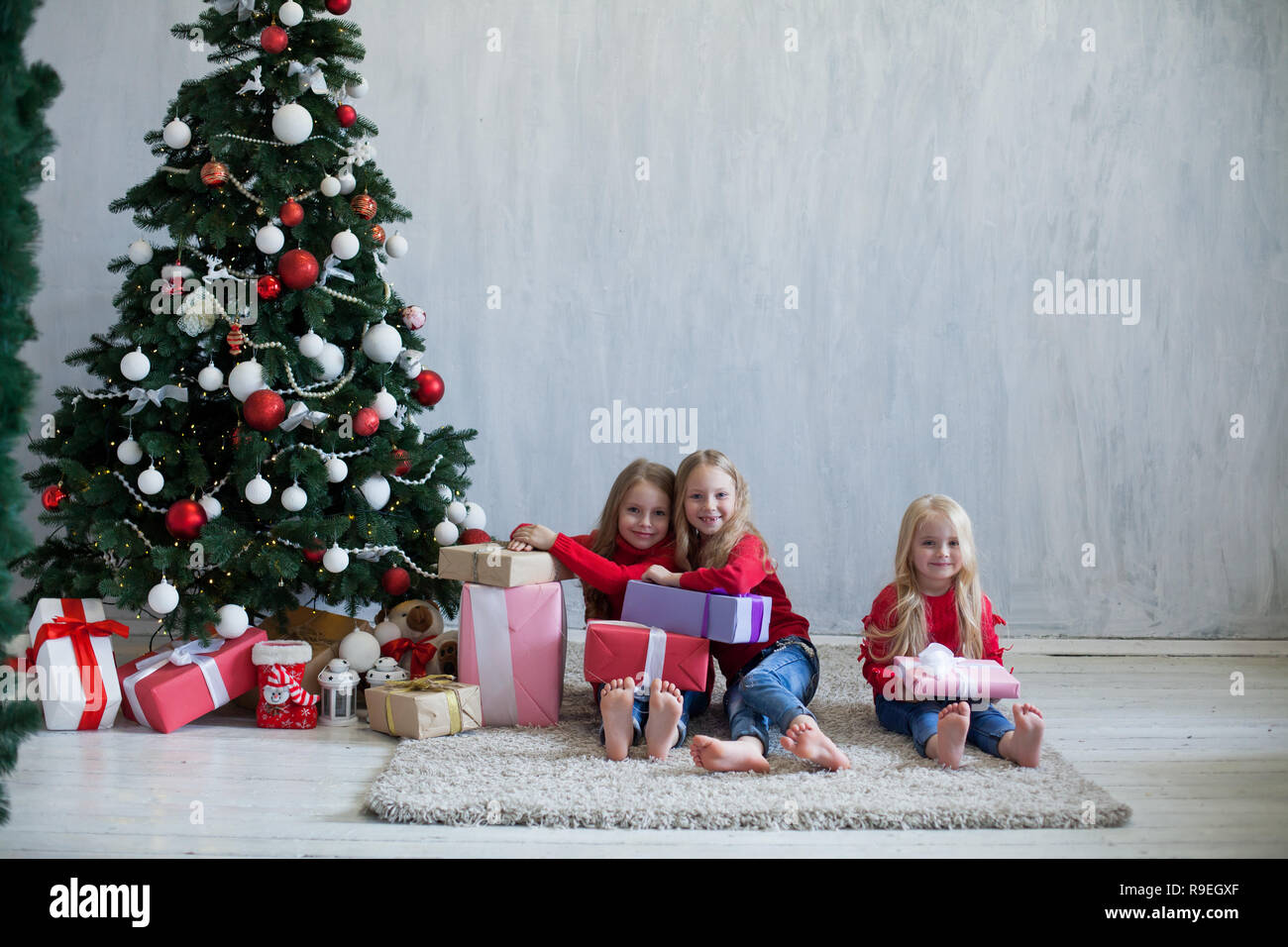 three girls opens Christmas presents new year Christmas tree Garland ...