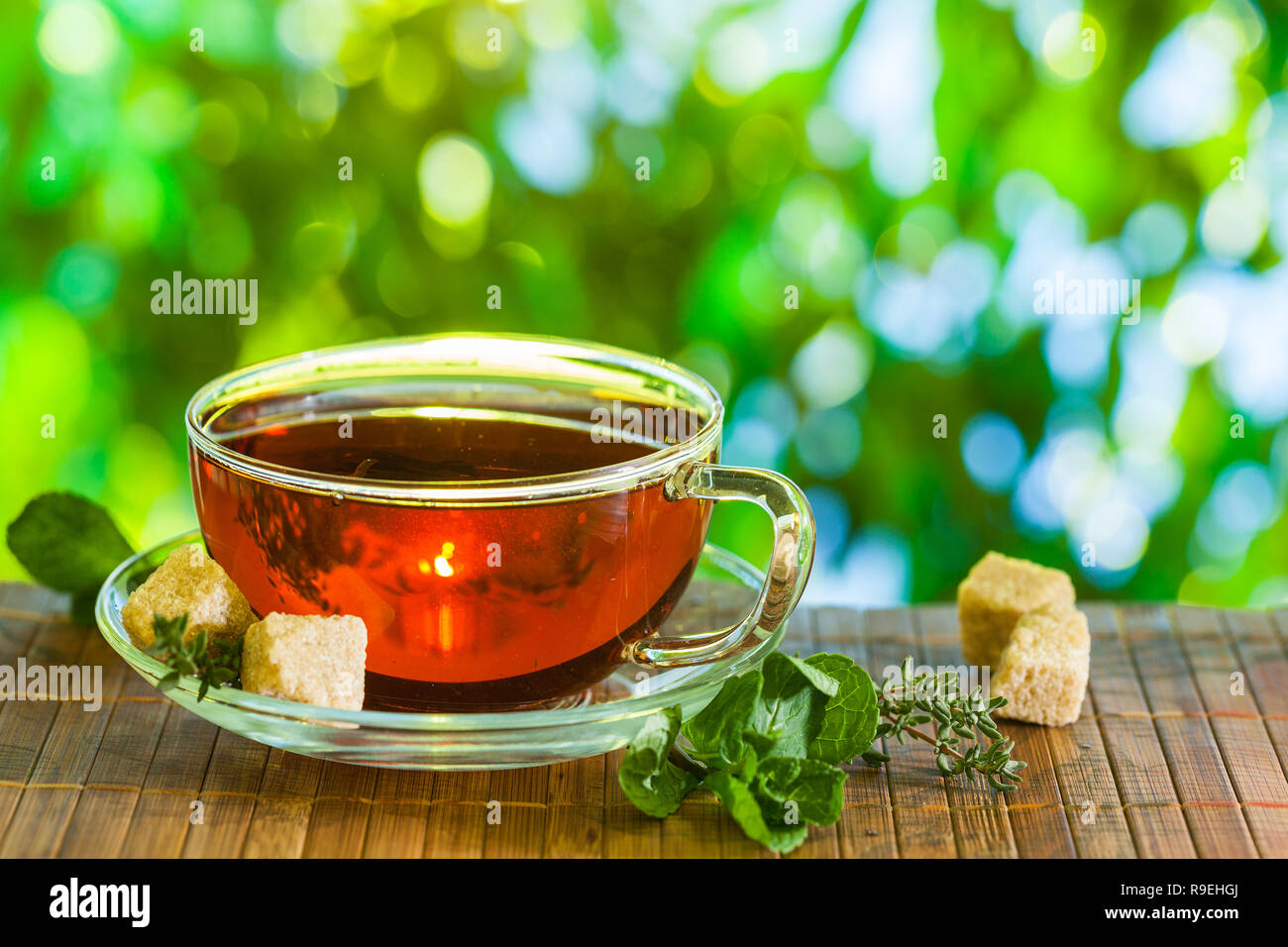 Tea time. Pouring out hot tea into a cup. Green nature background Stock ...