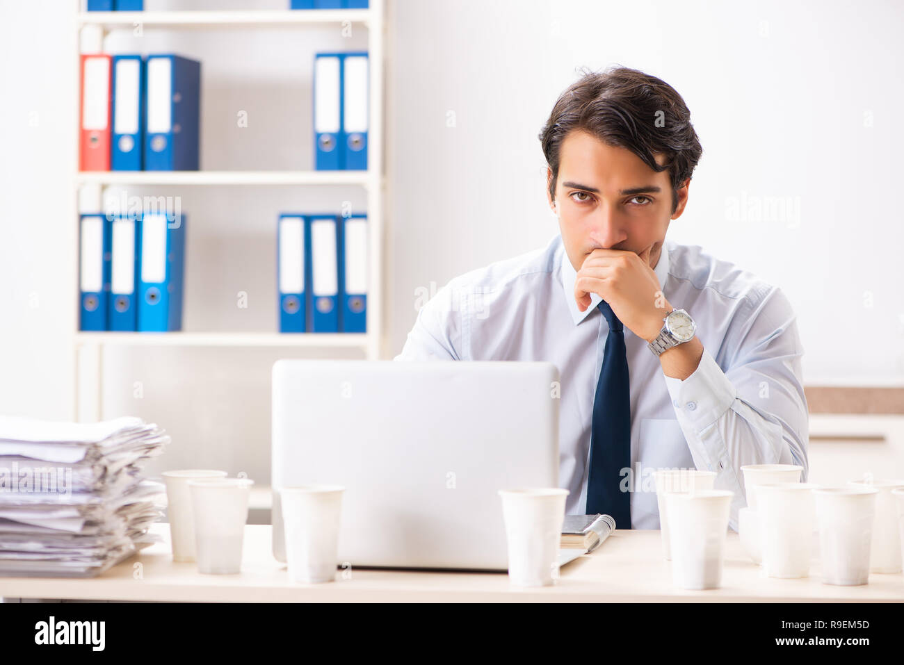 Young employee addicted to coffee Stock Photo - Alamy