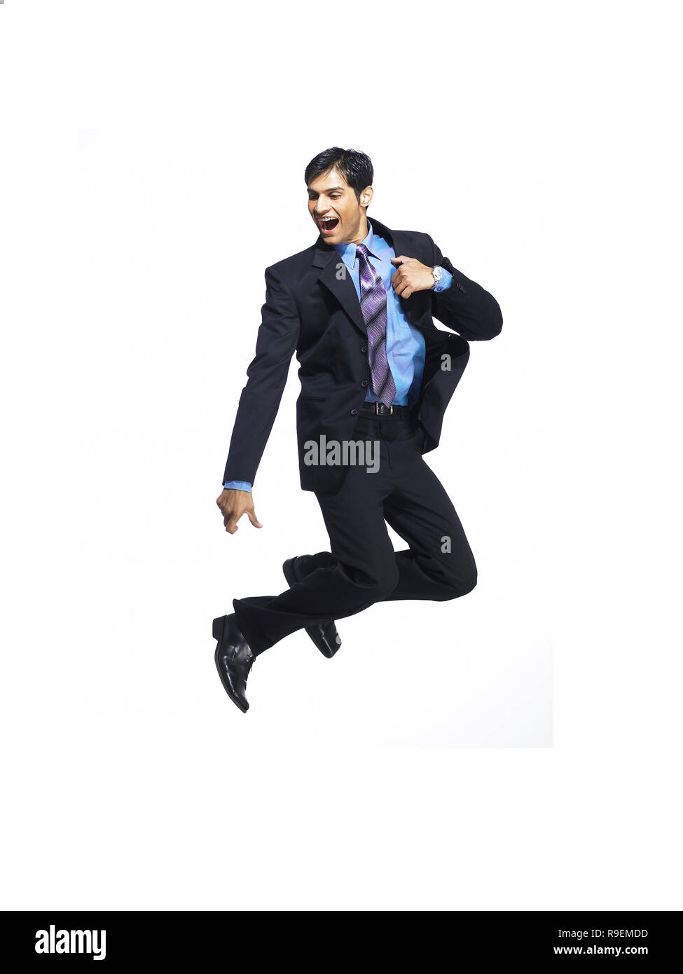 CORPORATE EXECUTIVE JUMPING IN EXUBERANCE WEARING A SUIT AGAINST A ...