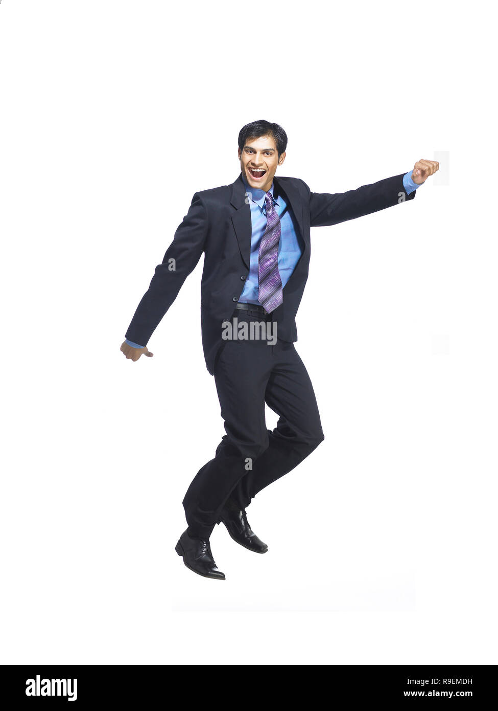 CORPORATE EXECUTIVE JUMPING IN EXUBERANCE WEARING A SUIT AGAINST A ...