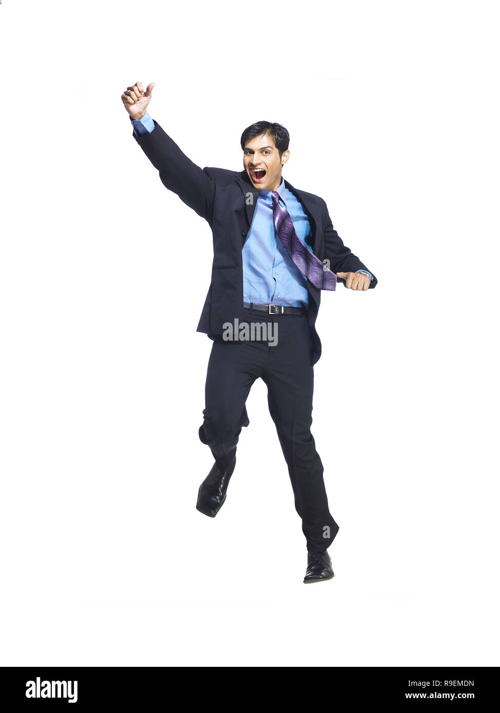 CORPORATE EXECUTIVE JUMPING IN EXUBERANCE WEARING A SUIT AGAINST A ...