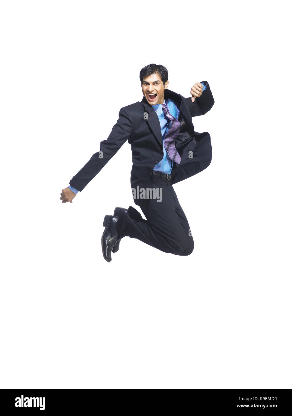 CORPORATE EXECUTIVE JUMPING IN EXUBERANCE WEARING A SUIT AGAINST A ...