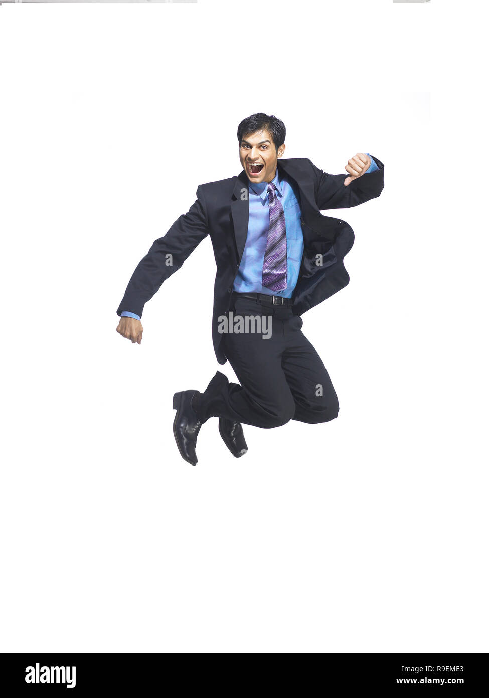 CORPORATE EXECUTIVE JUMPING IN EXUBERANCE WEARING A SUIT AGAINST A ...
