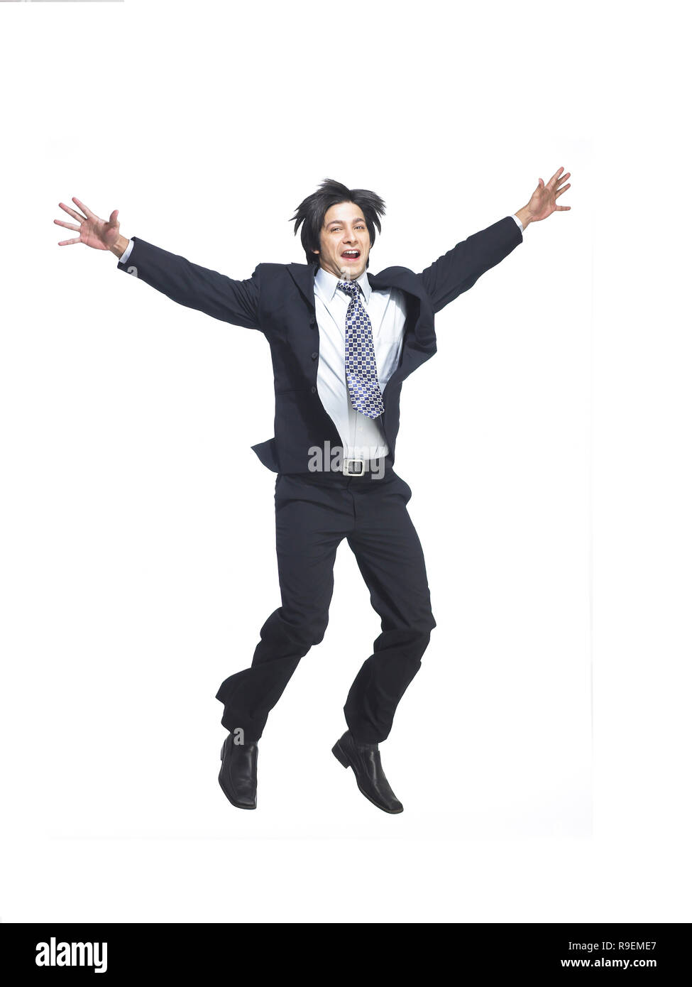 CORPORATE EXECUTIVE JUMPING IN EXUBERANCE WEARING A SUIT AGAINST A ...