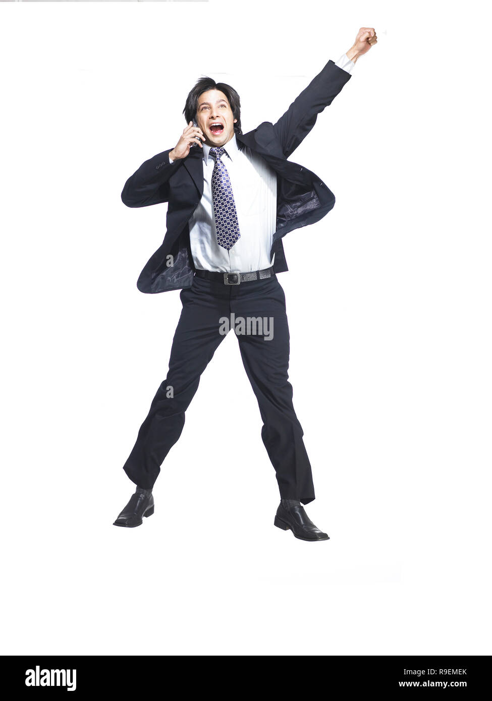 CORPORATE EXECUTIVE JUMPING IN EXUBERANCE WEARING A SUIT AGAINST A ...
