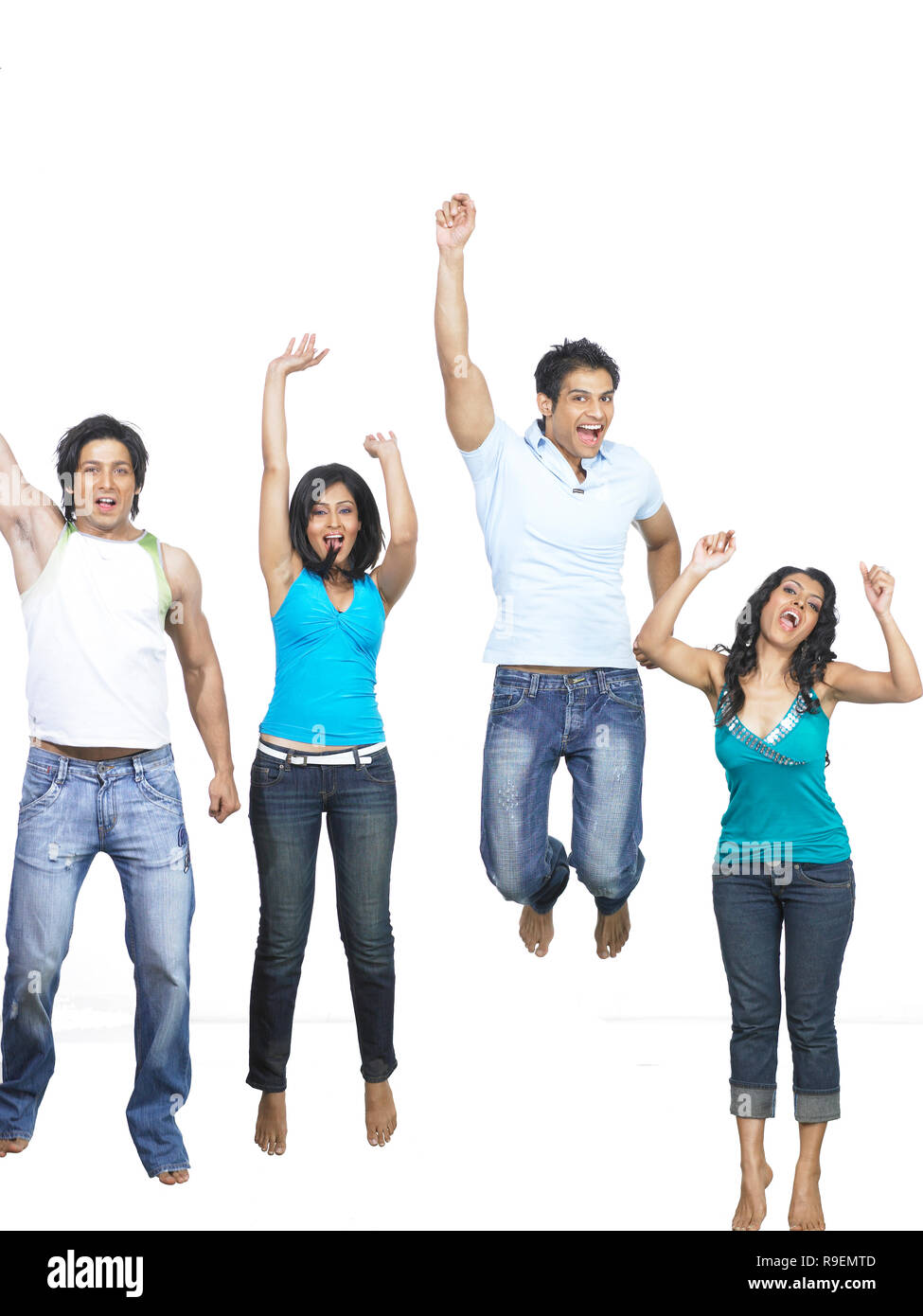 TWO YOUNG COUPLES JUMPING IN EXUBERANCE AGAINST A WHITE BACKGROUND ...
