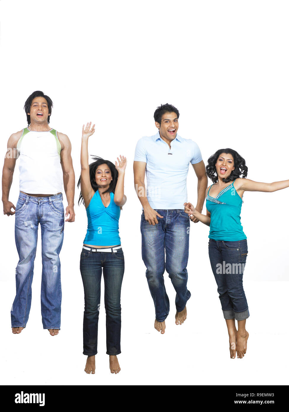 TWO YOUNG COUPLES JUMPING IN EXUBERANCE AGAINST A WHITE BACKGROUND ...