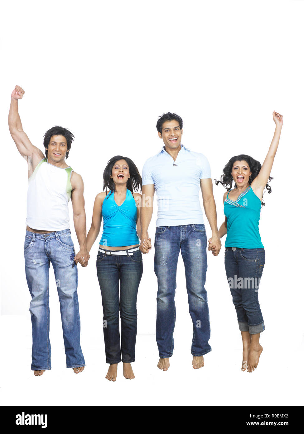 TWO YOUNG COUPLES JUMPING IN EXUBERANCE AGAINST A WHITE BACKGROUND ...
