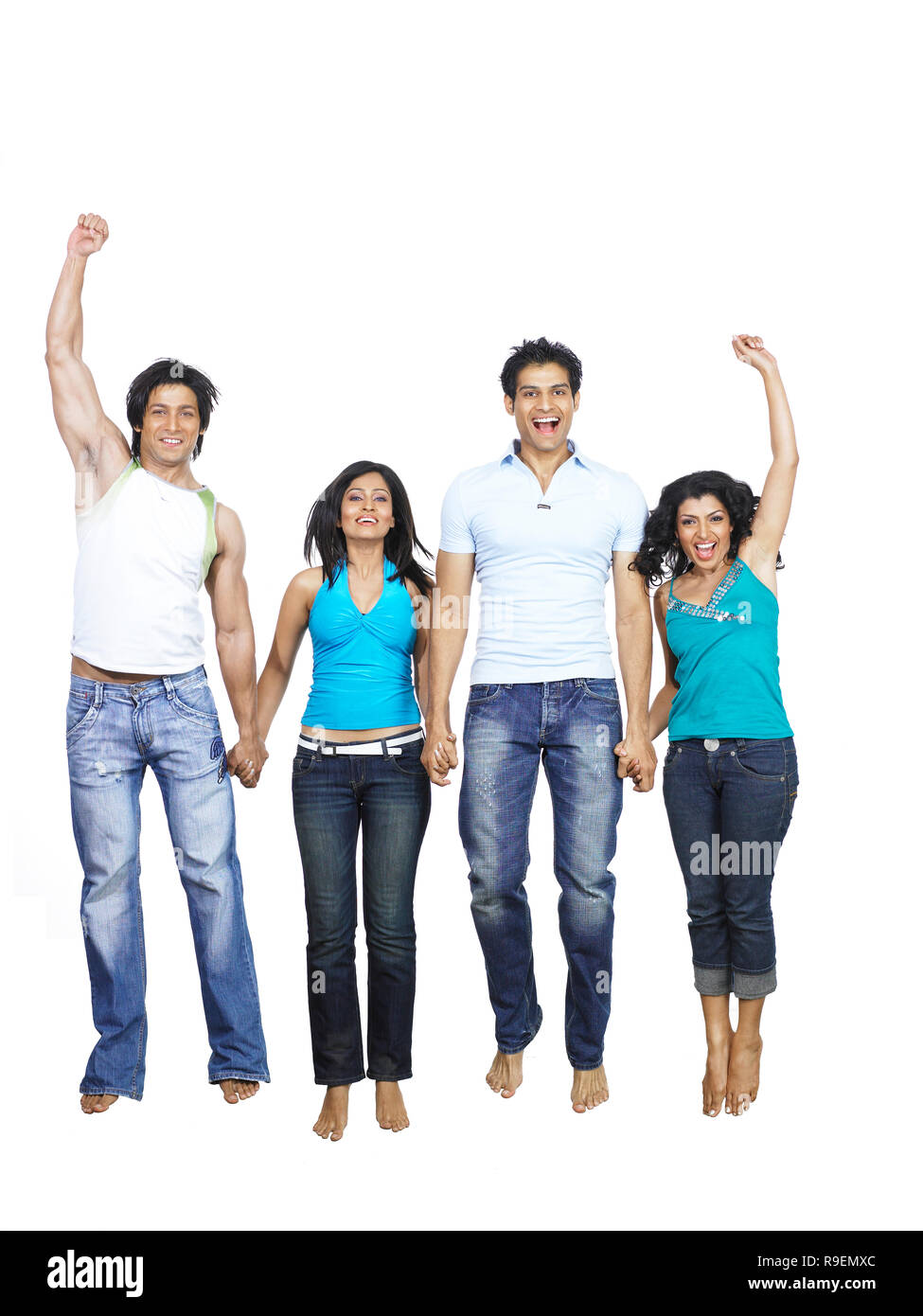 TWO YOUNG COUPLES JUMPING IN EXUBERANCE AGAINST A WHITE BACKGROUND ...