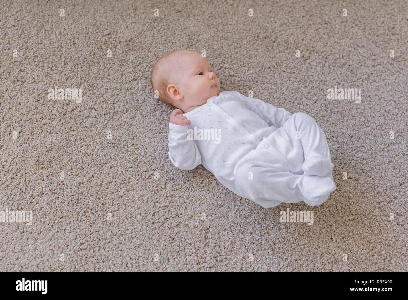 Childhood, infant and people concept - small baby lying on the floor ...
