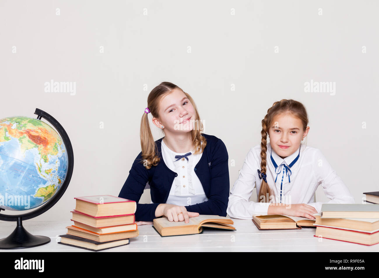 two girls in the classroom Learn lesson books at her desk globe Stock ...